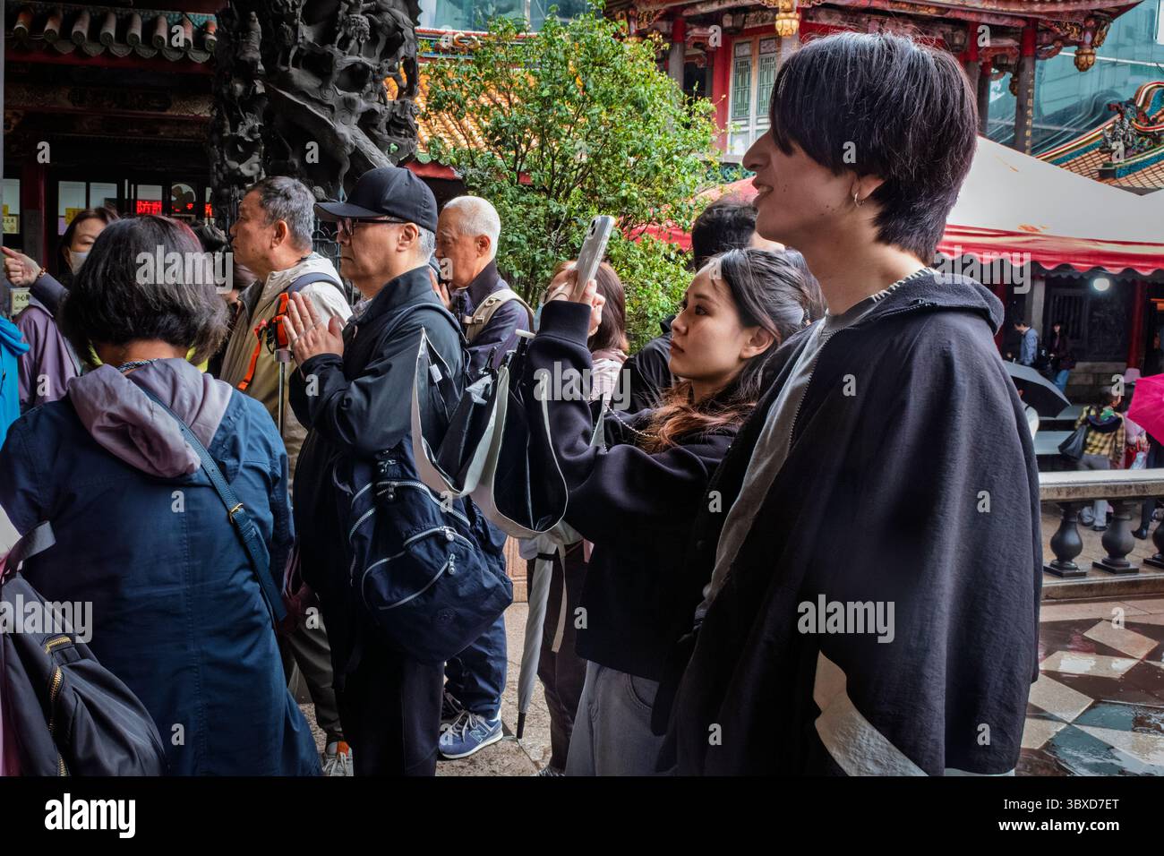 Tourists taking photographs and worshippers at the Lungshan Temple ...