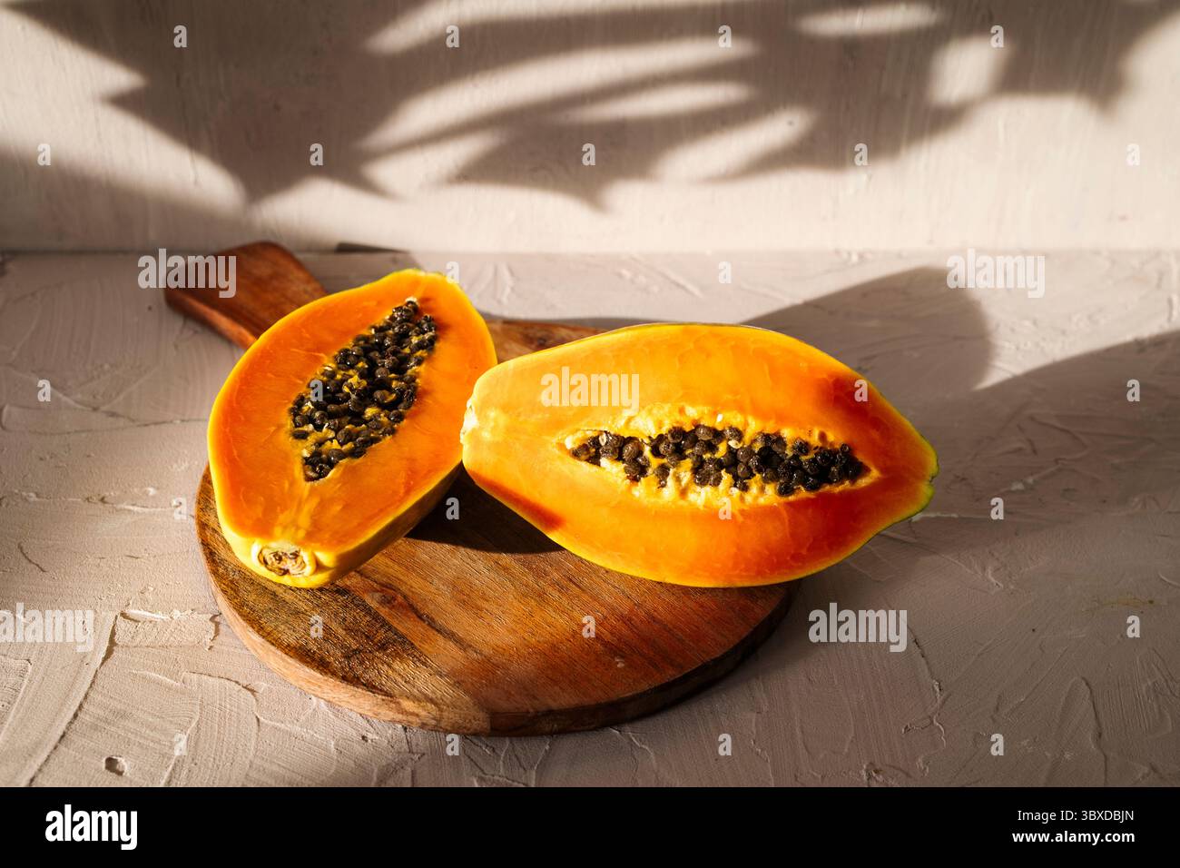 A freshly cut ripe papaya displayed on a clean surface with soft shadow ...