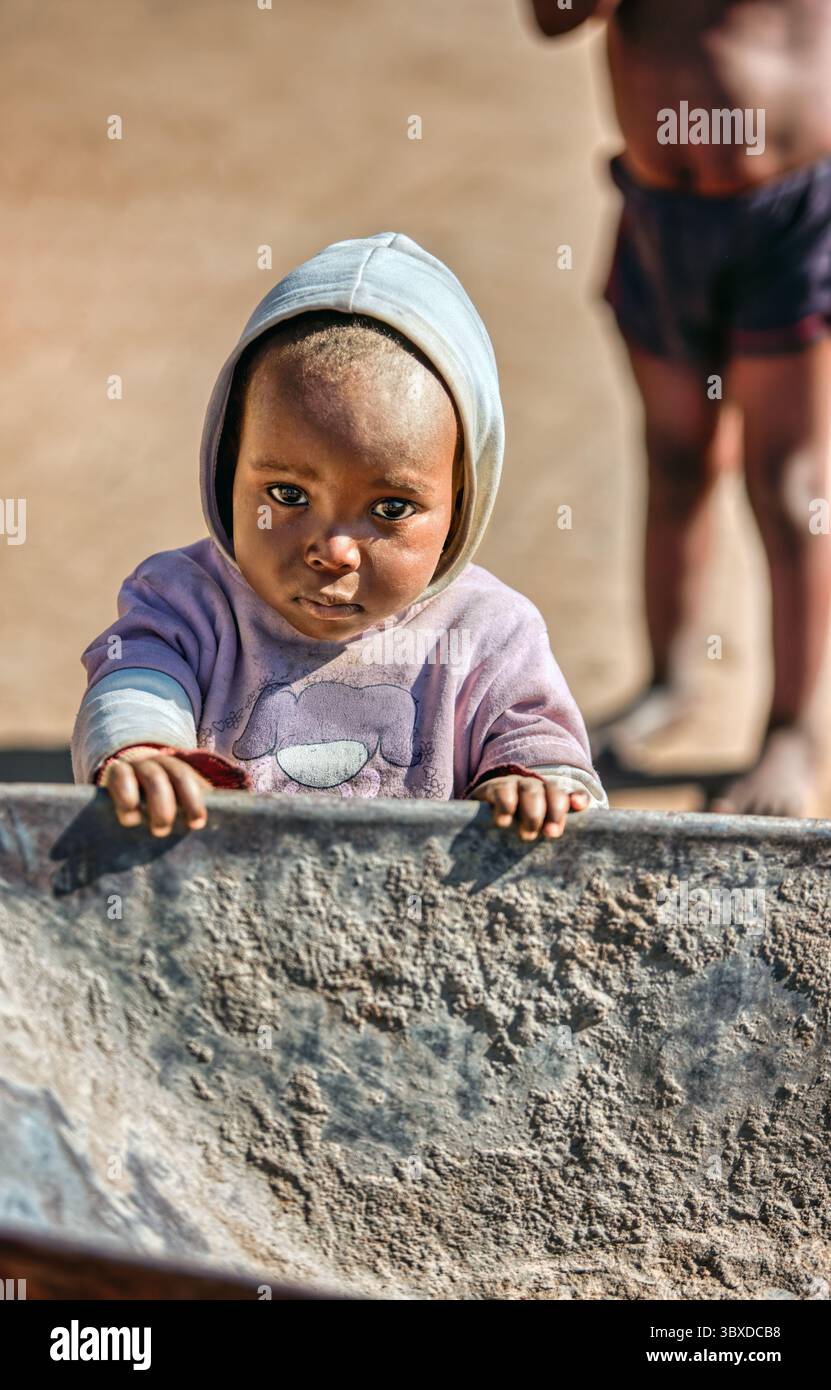 african child, village in Botswana , holding a wheelbarrow, standing in ...