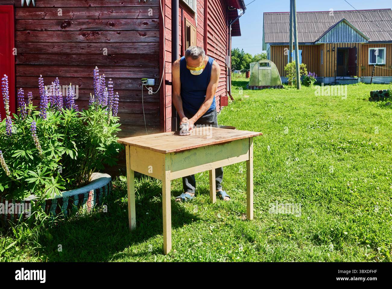 Sanding wooden tabletop with angle grinder outdoors, hobbyist working ...