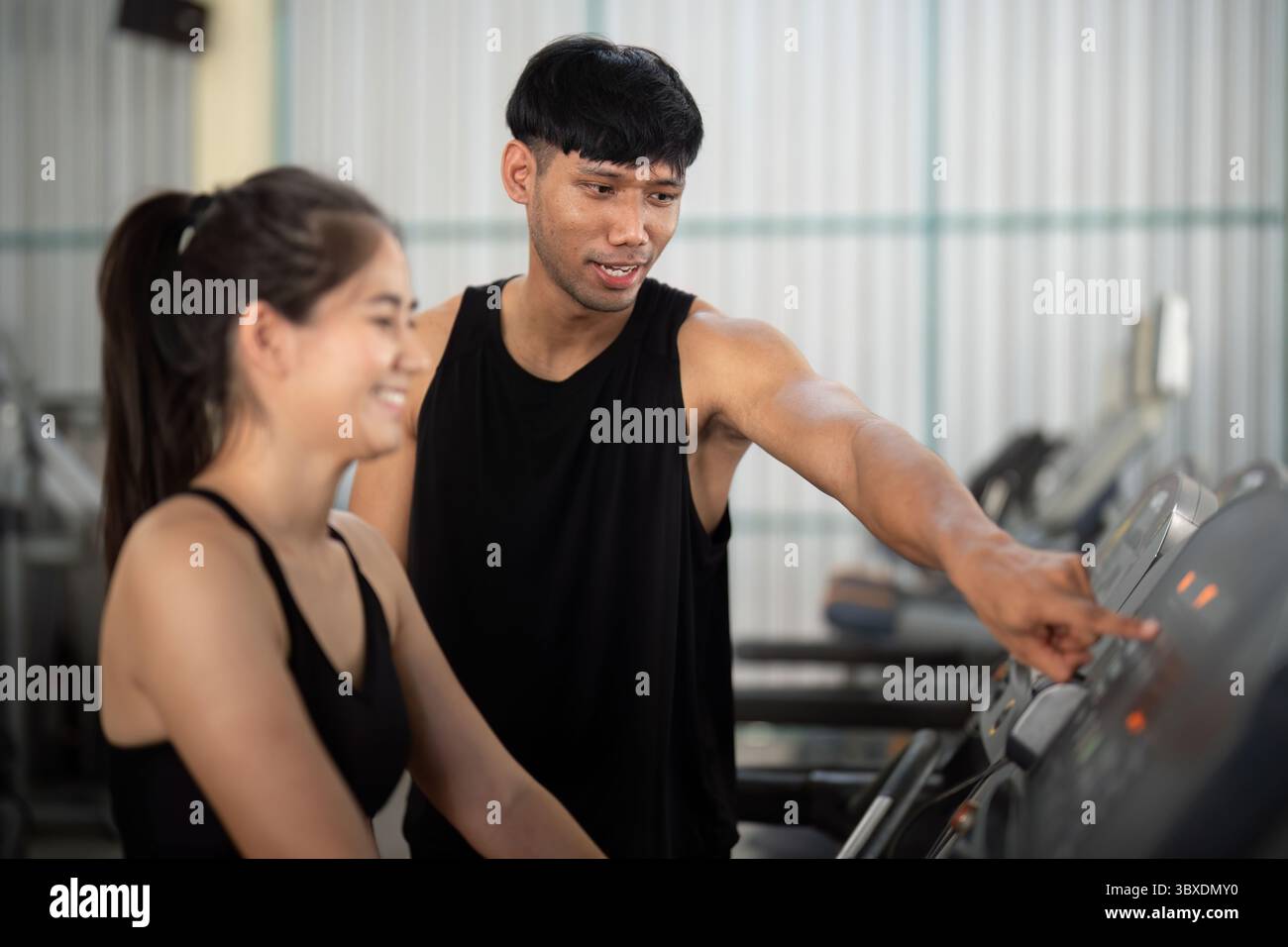 Trainer demonstrating treadmill settings to female athlete Stock Photo ...