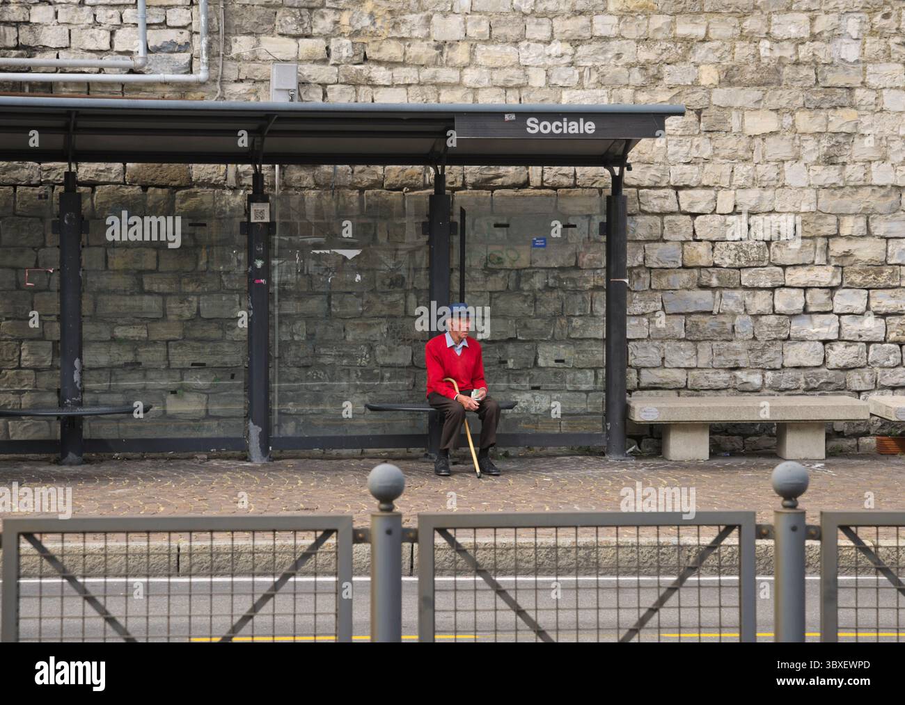 old man sitting on a bench at the bus stop, Italy Stock Photo - Alamy