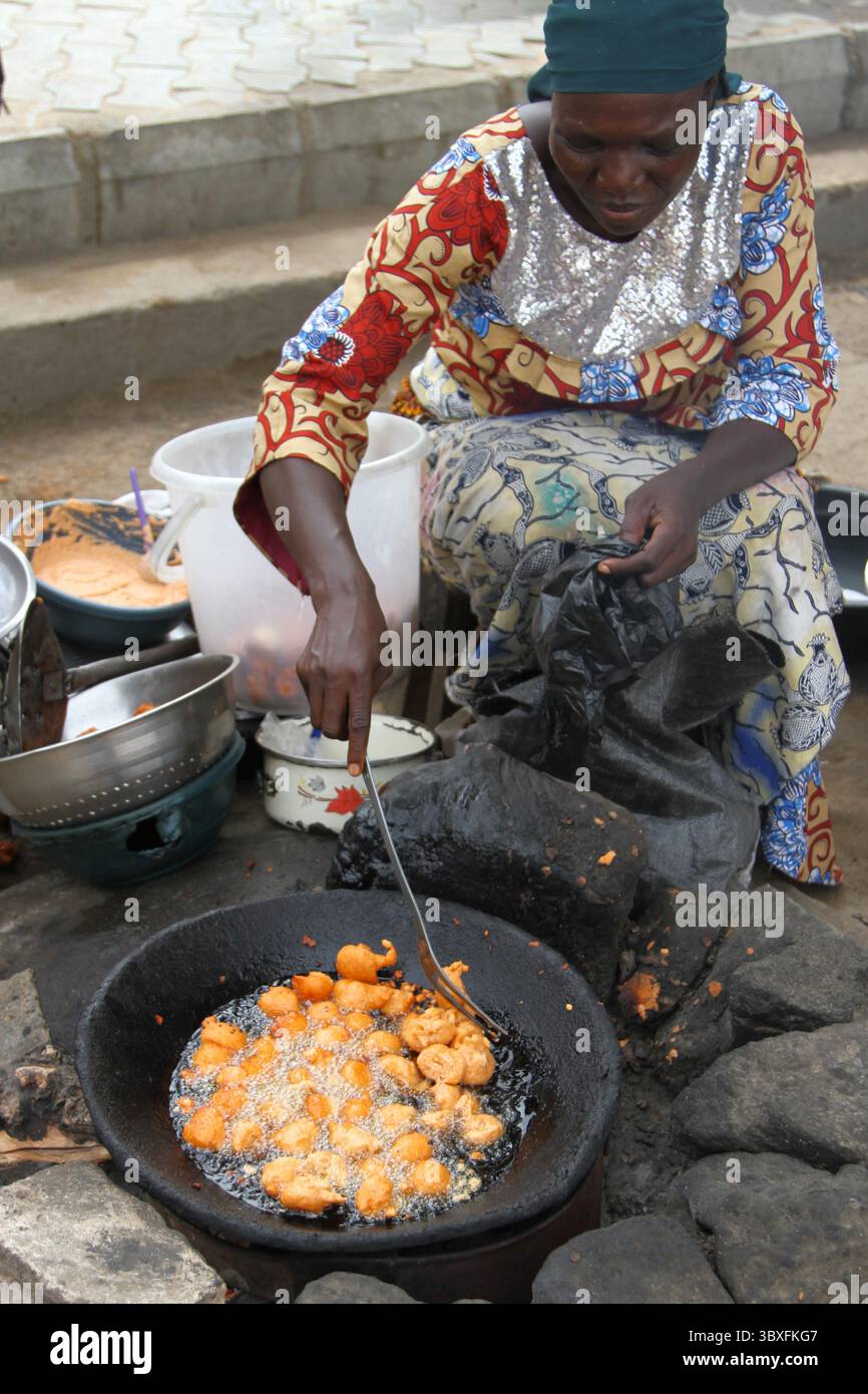 A Nigerian woman dressed in traditional African clothing frying Akara ...