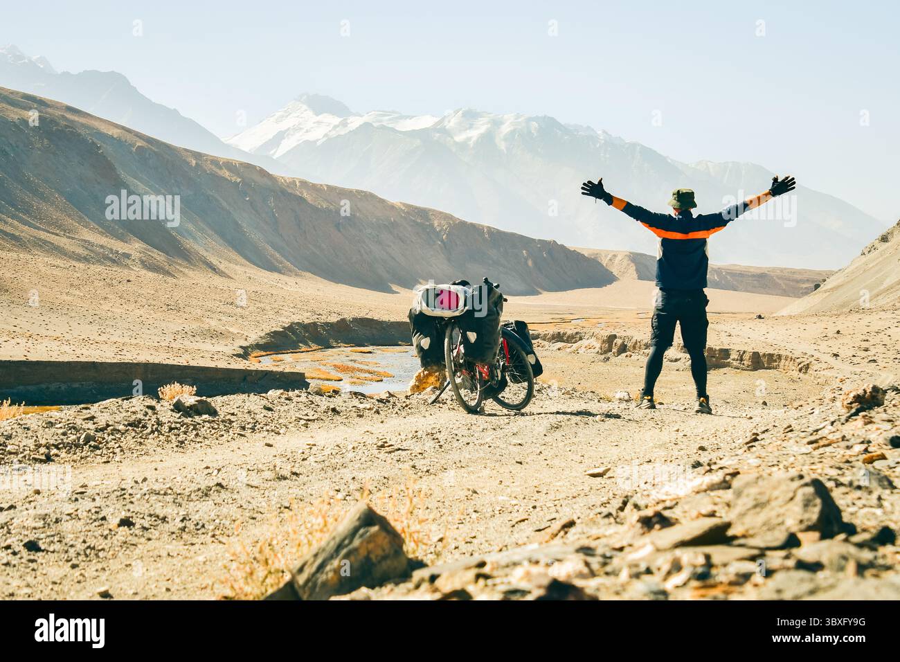 Adventurous caucasian male traveller arms up enjoy views cycle bicycle ...