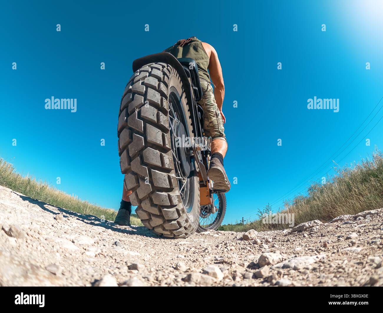 Creative photo of zoomed electric motorcycle wheel with biker on road ...