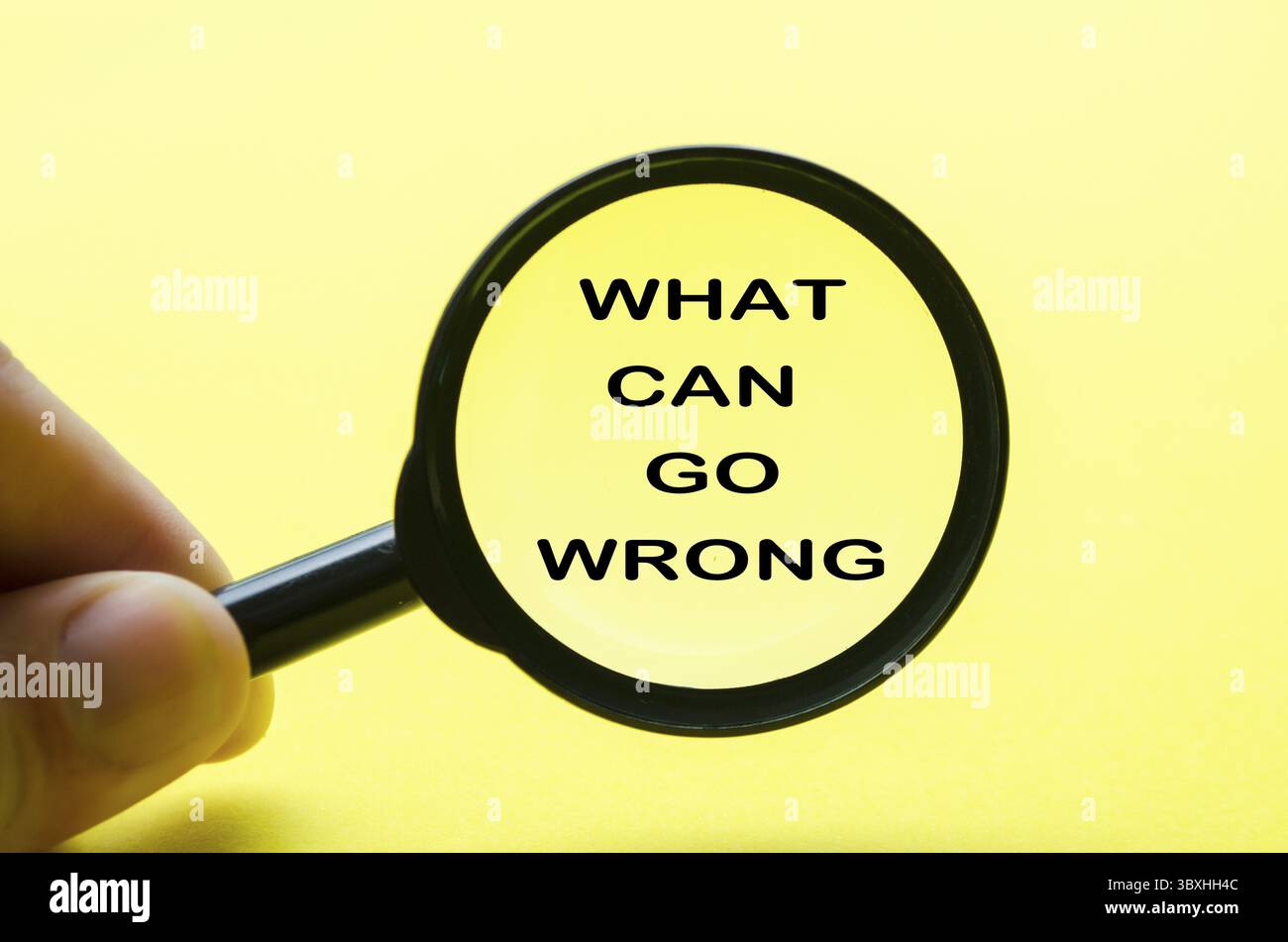 Hand holding magnifying glass with text what can go wrong. Fact finding ...