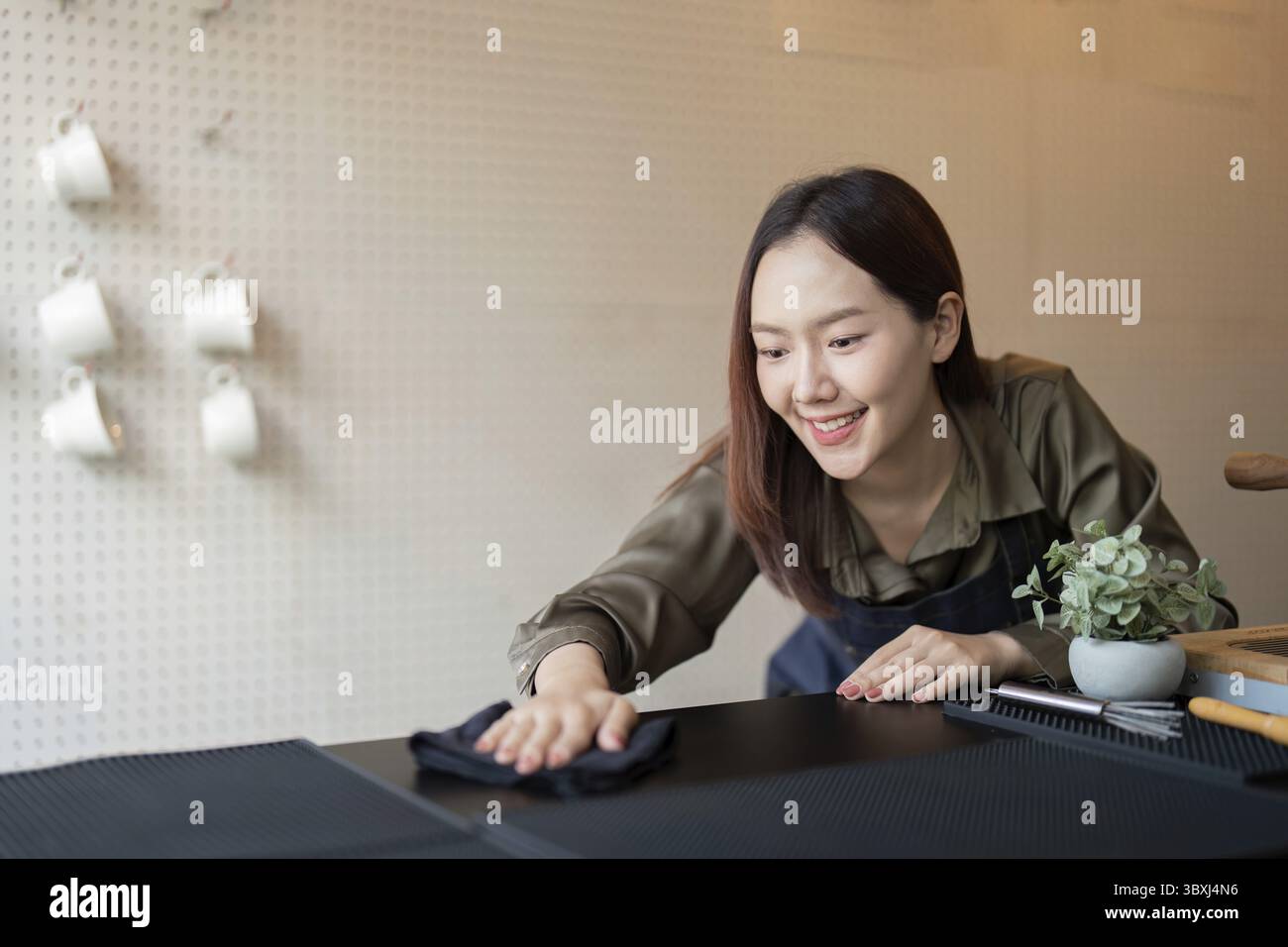 A barista smiles while cleaning the counter, showcasing her commitment ...