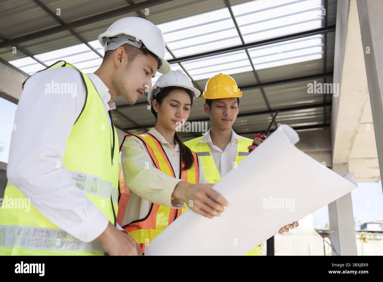 A team of engineers analyzing blueprints together on a construction ...