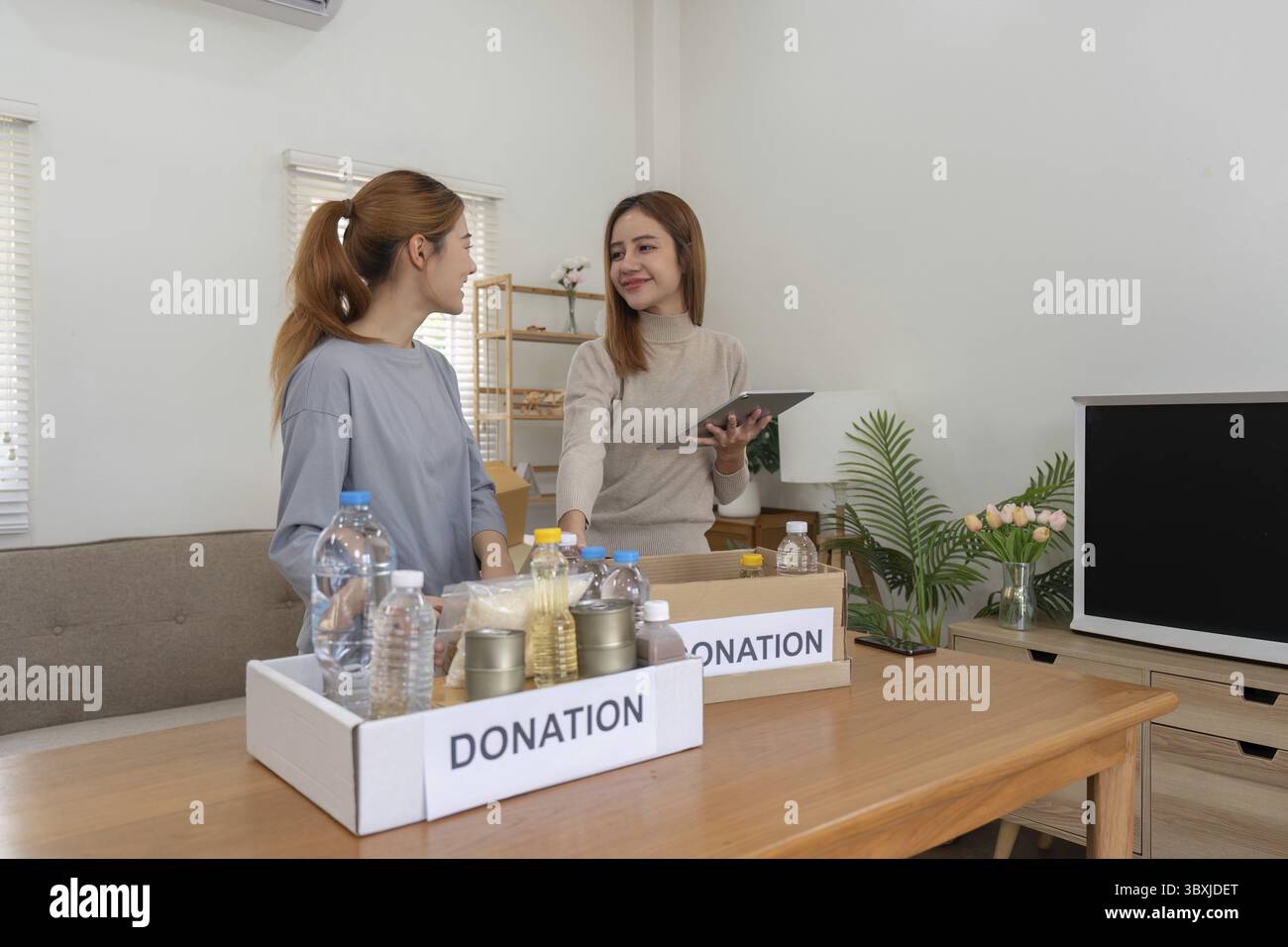 Two volunteers sorting and organizing donation items in a modern ...