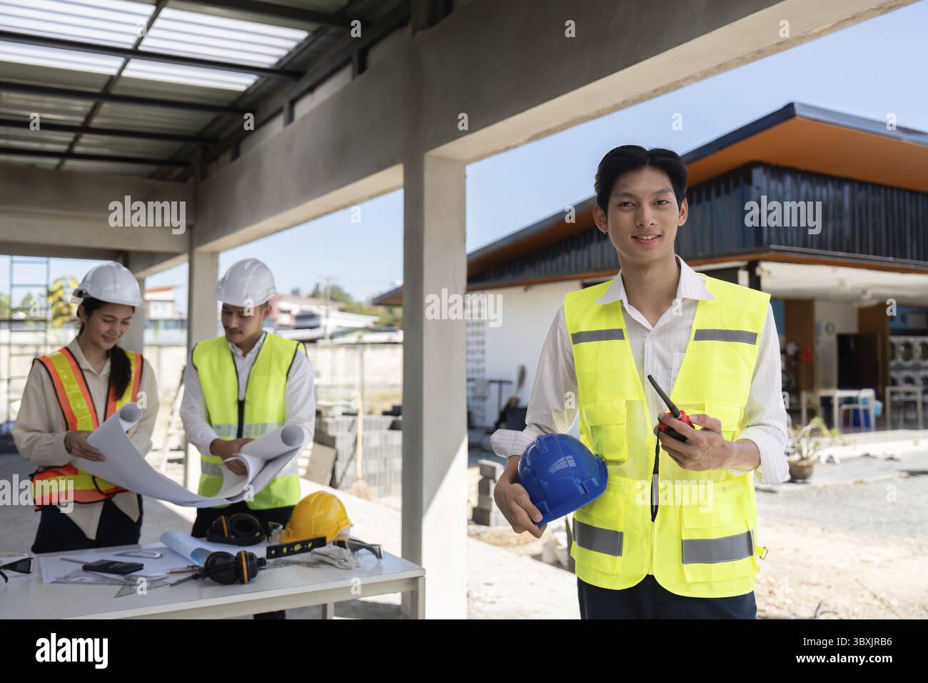 A young construction worker holding a helmet and radio, highlighting ...