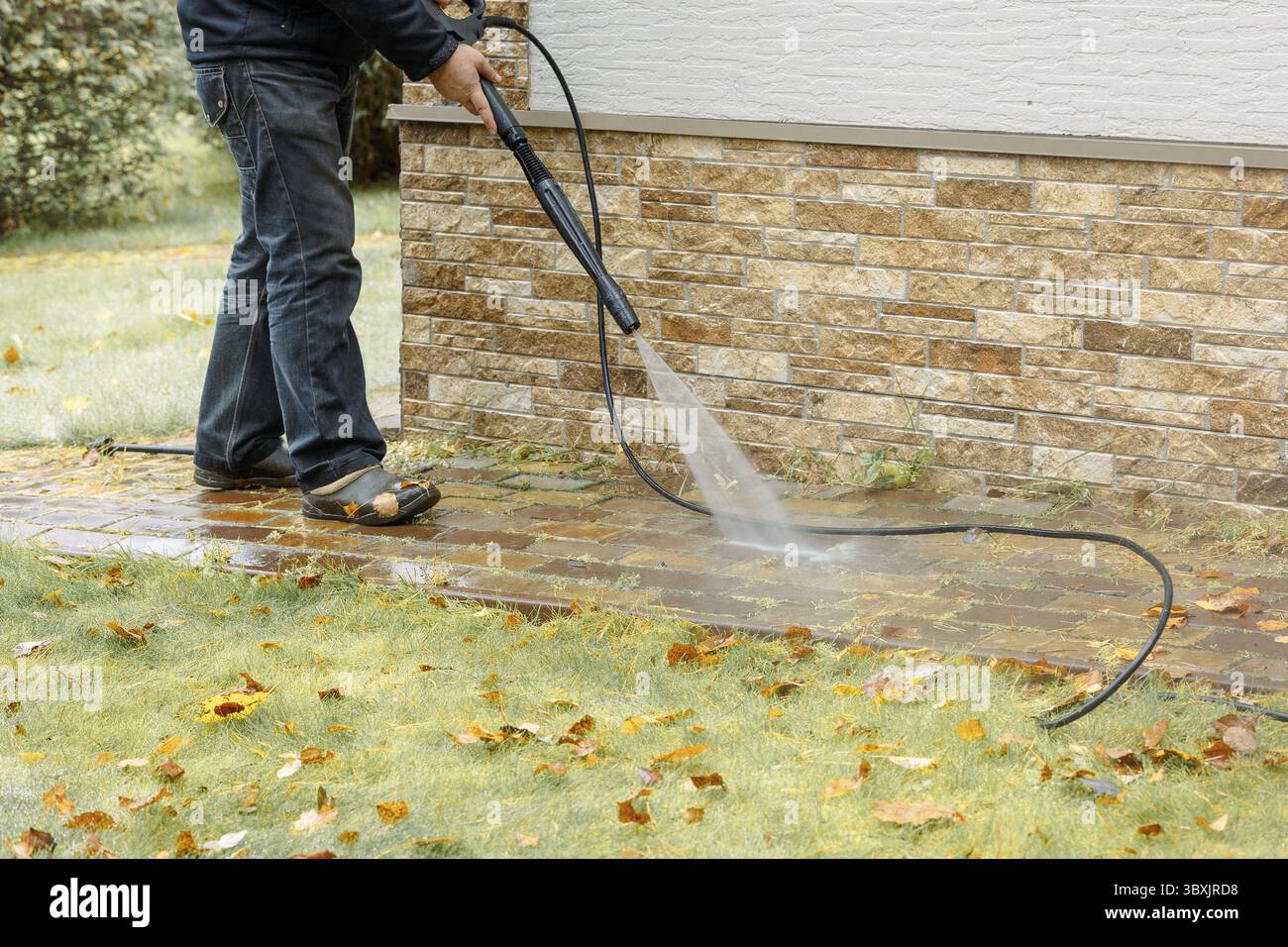 Man cleaning street with high pressure power washer, washing stone ...