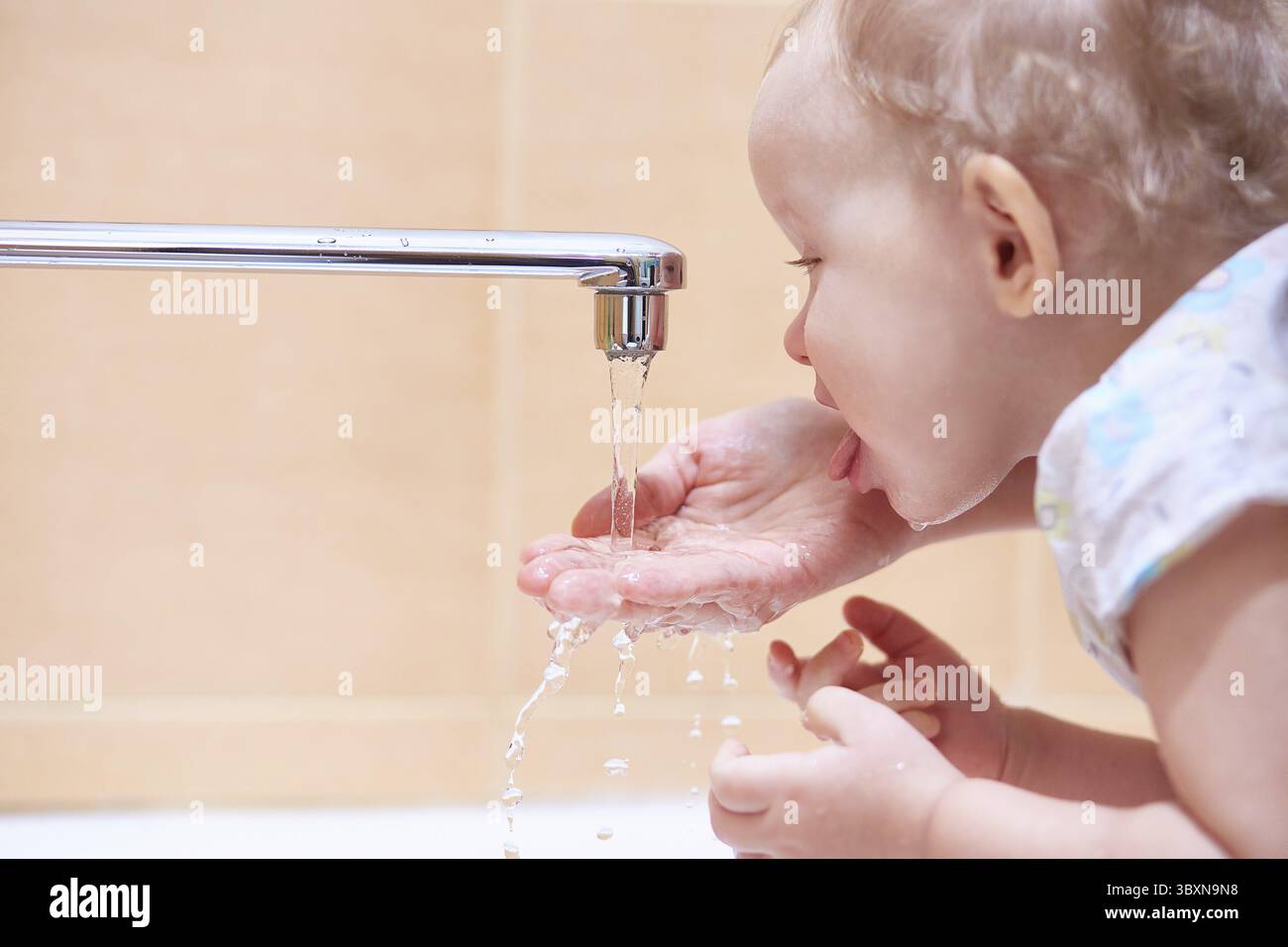 The child drinks running water from the tap Stock Photo - Alamy