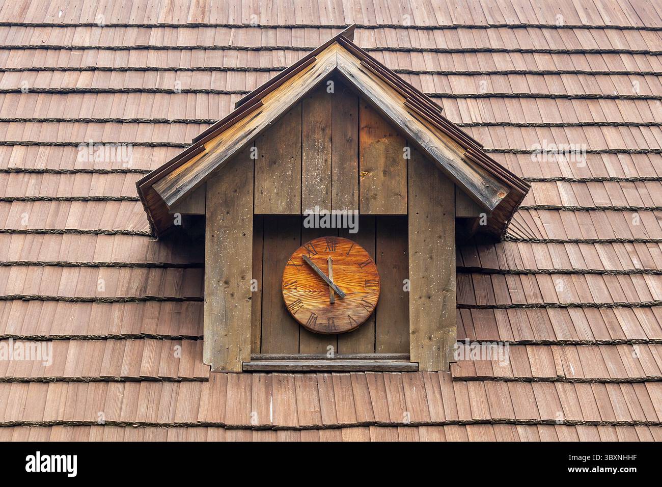 An old historic dormer with a wooden clock on a shingled roof Stock ...