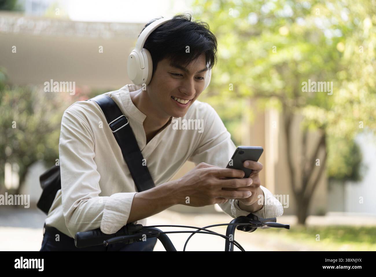 An individual enjoys his bike ride while smiling at his phone ...