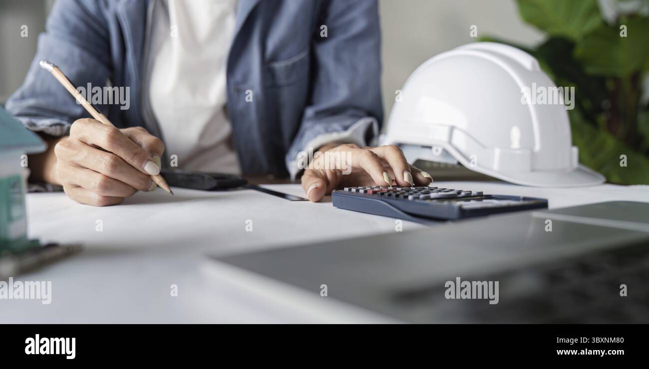An engineer hands using a calculator to determine project costs, with a ...