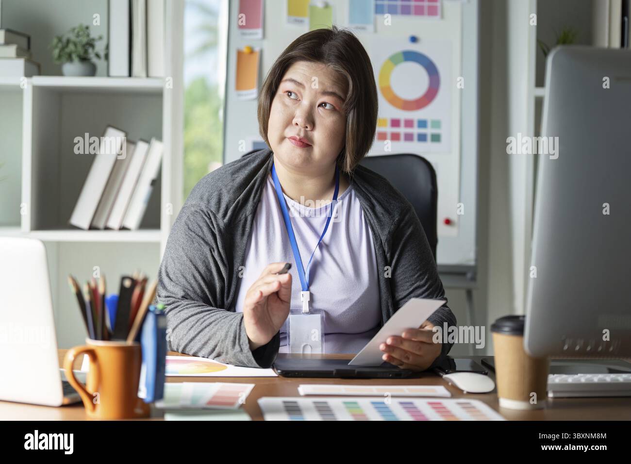 A thoughtful graphic designer in an office setting, surrounded by color ...