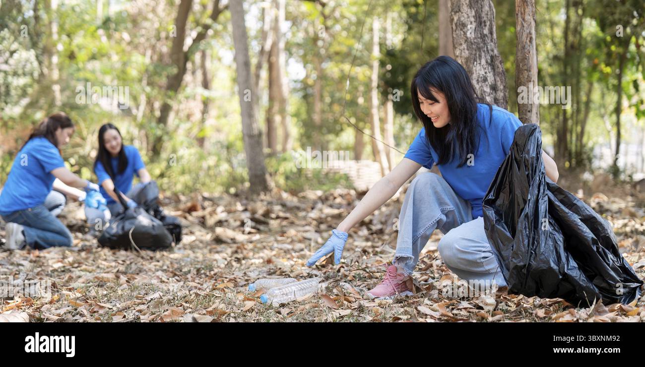 A group of young women in blue shirts actively picking up litter in a ...