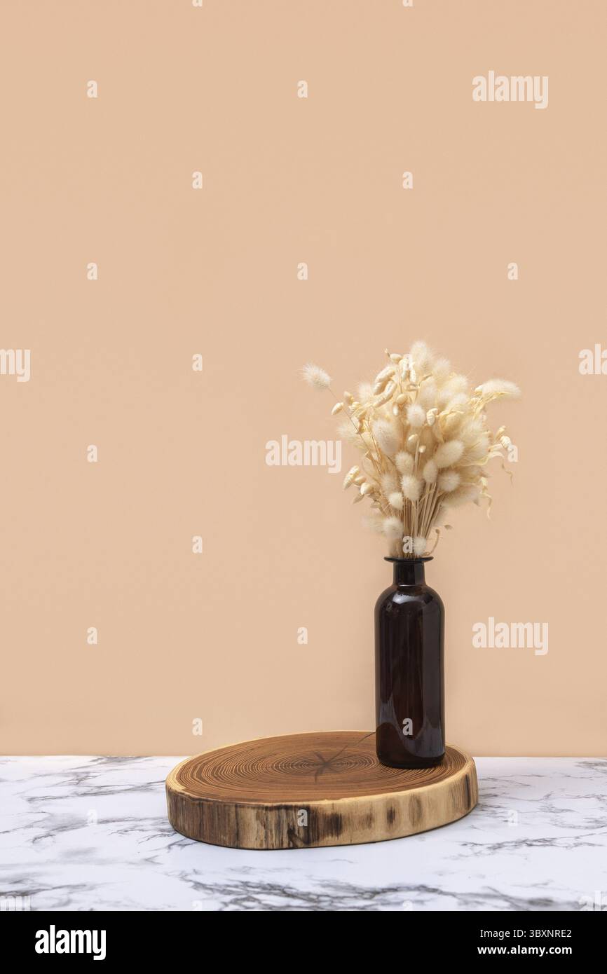 Dry bouquet of spikelets in dark glass bottle on marble table with ...