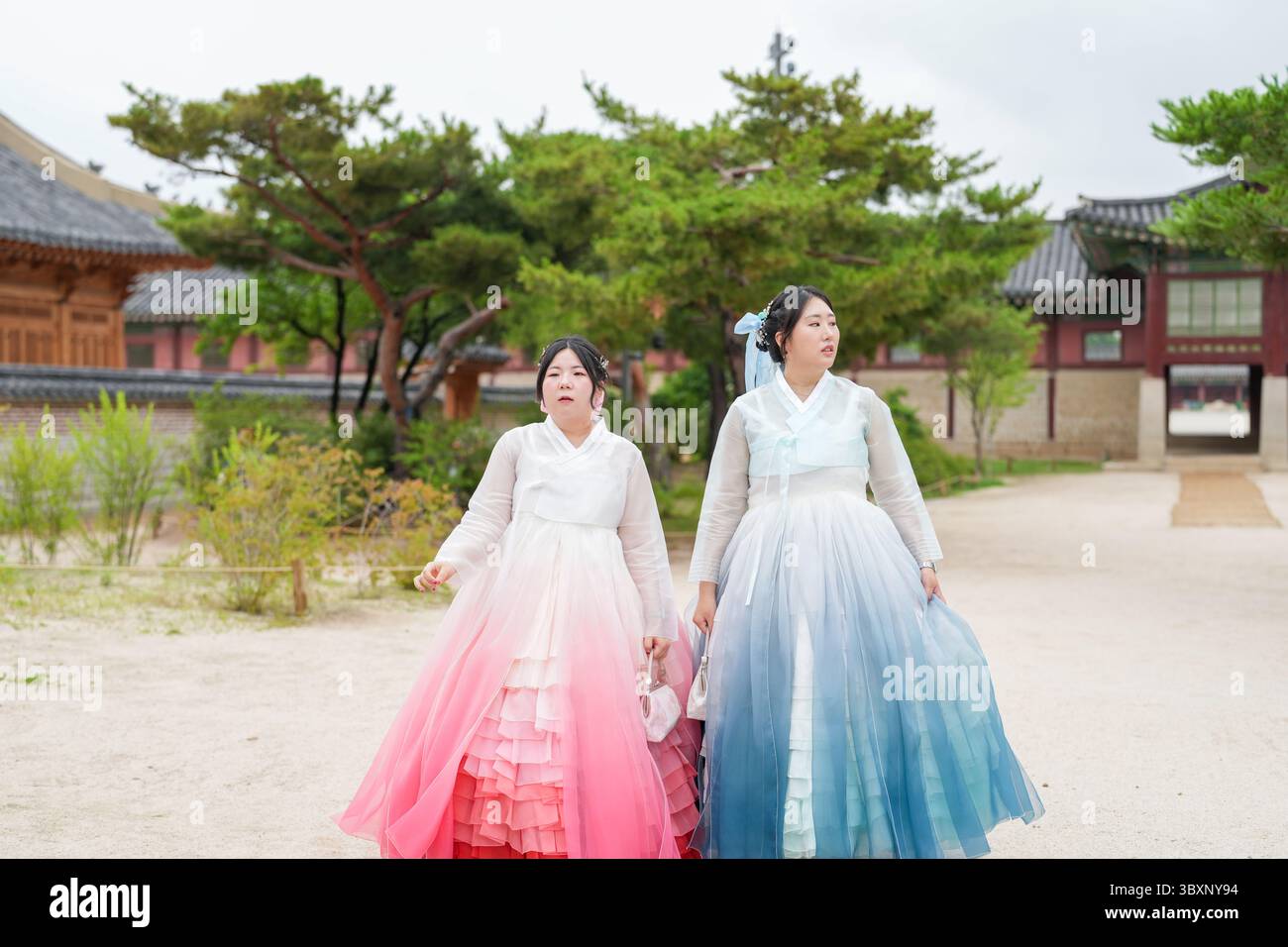 In June in Seoul, two Korean women in their twenties walk among lush ...