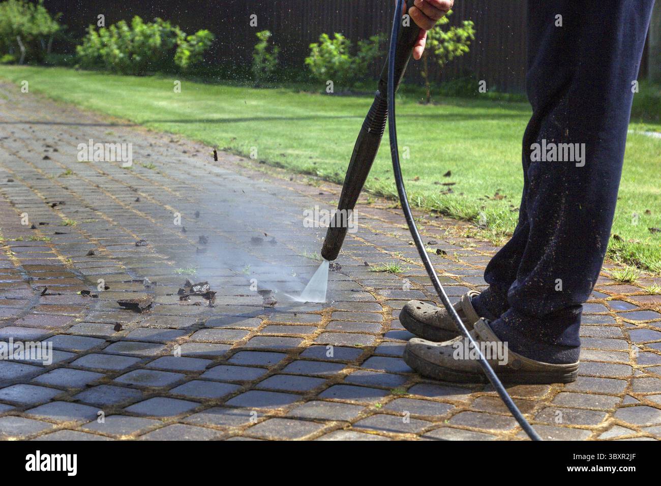 Cleaning street with high pressure power washer, washing stone garden ...