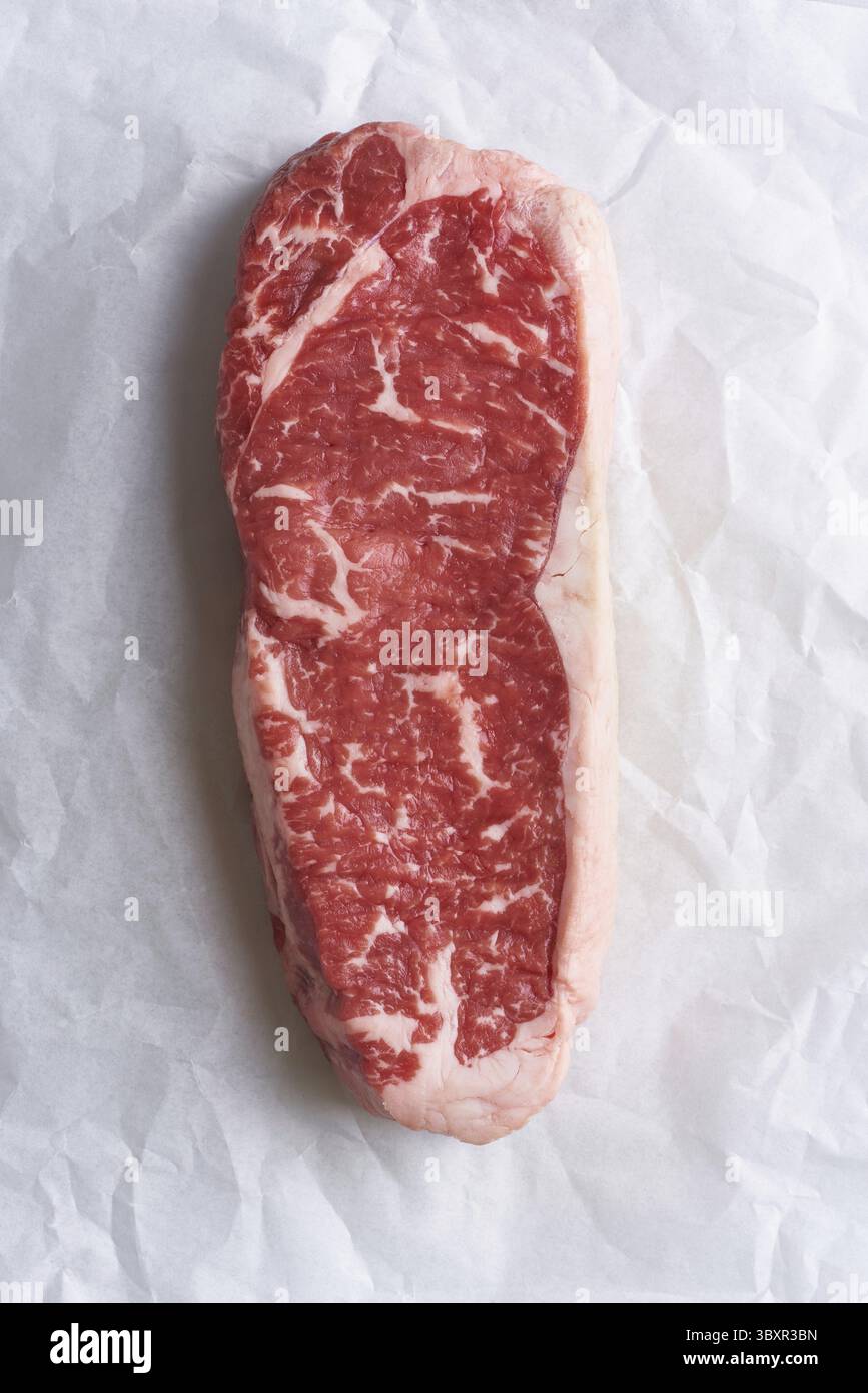 Big whole piece of raw beef meat, striploin on white parchment paper on ...