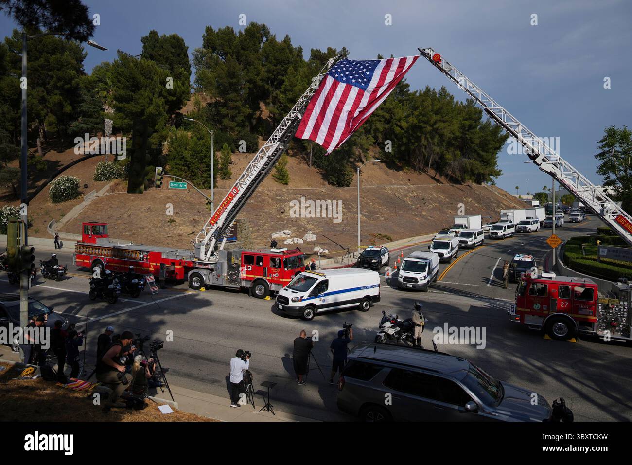 Medical examiner vans are driven along a procession route near where an ...
