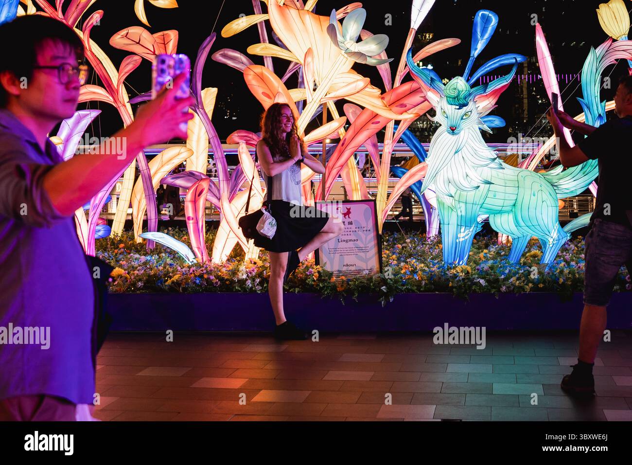 A visitor strikes a pose next to "Lingmao," a mythical glowing creature ...