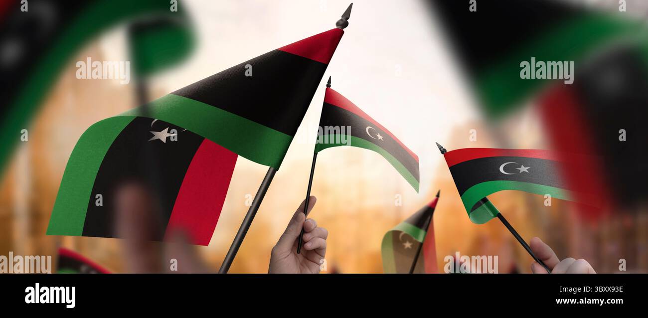 Libya flags in their hands on a blurred urban background Stock Photo ...