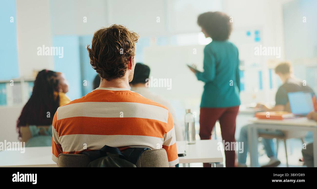 Man, student and back view with teacher in classroom for learning or higher education in ...