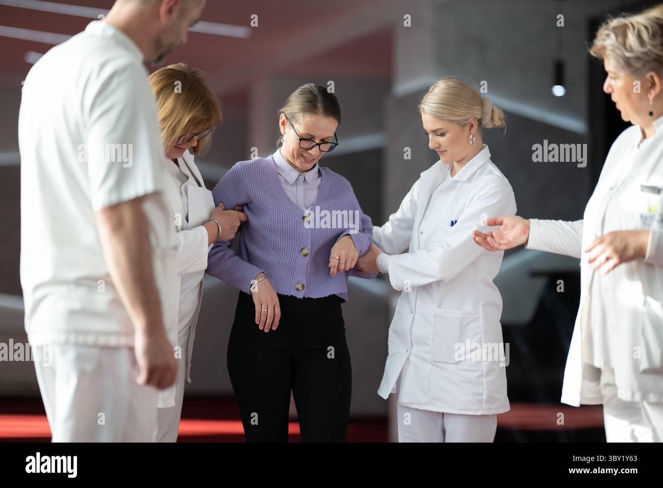 Medical team helping patient with walking therapy Stock Photo - Alamy