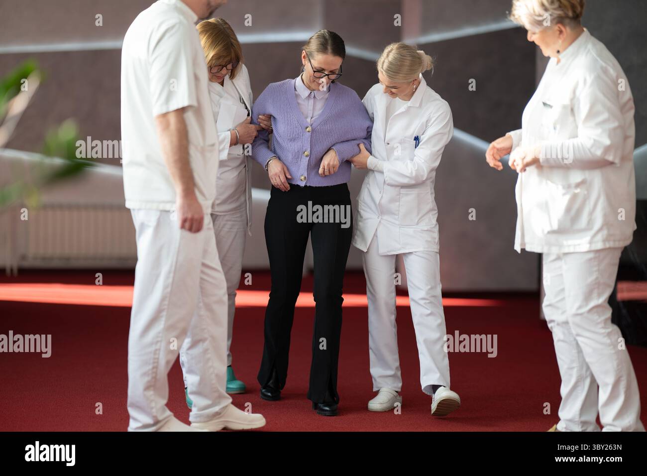 Medical team helping patient with walking therapy Stock Photo - Alamy
