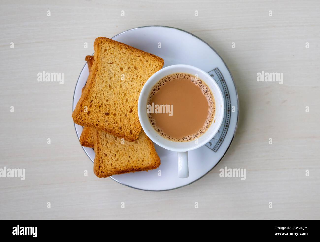 Hot milk tea with frothy bubbles and crispy rusk biscuits on wood ...