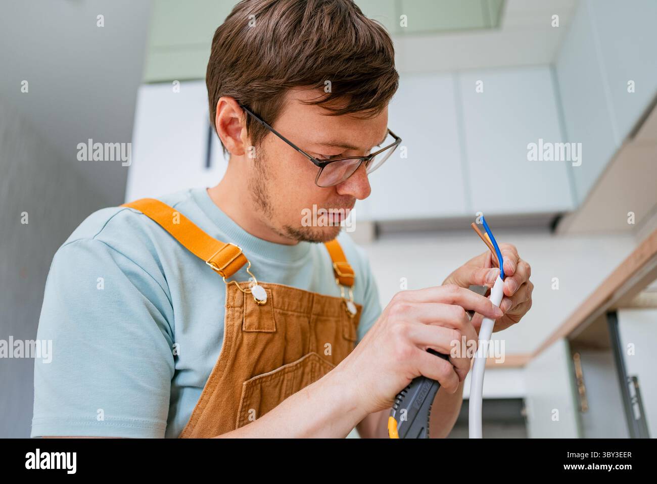 Skilled electrician stripping wire insulation with precision tool ...
