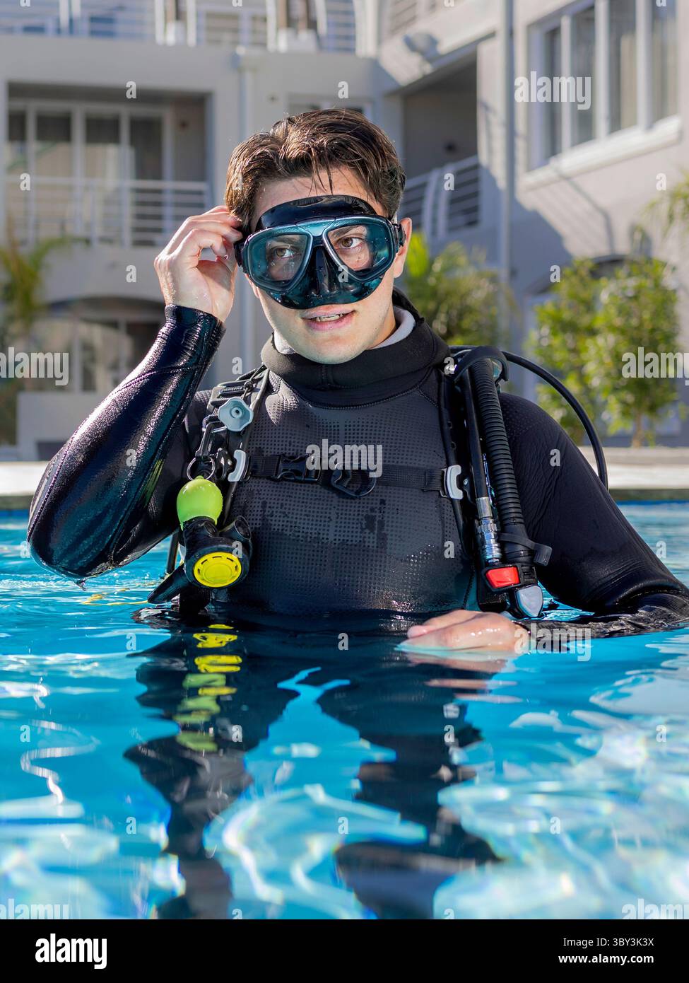A scuba diver in a pool at a dive resort, wearing a full wetsuit and ...