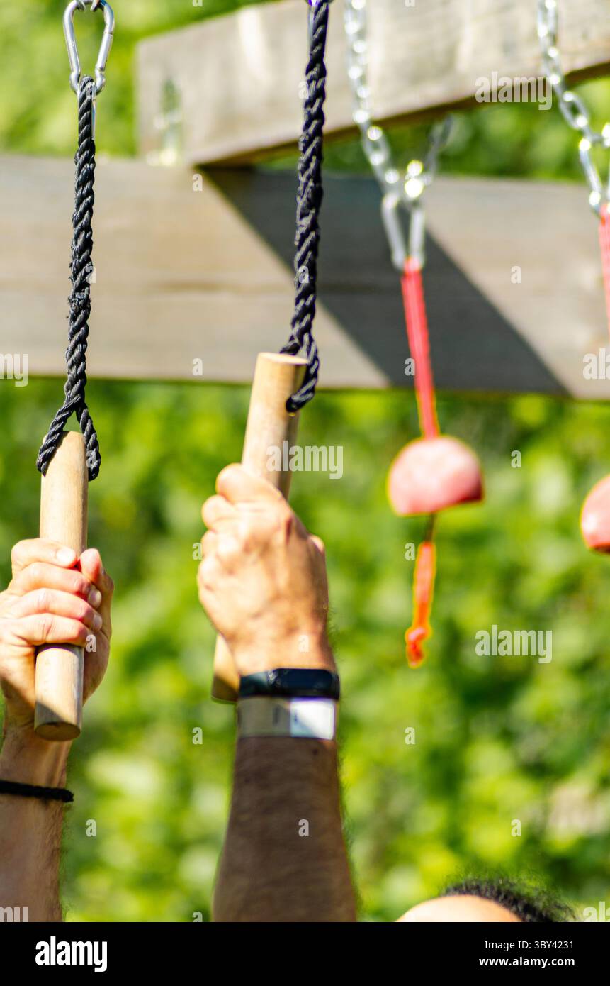Detail of hands and arms on monkey bar style obstacles. Two people ...