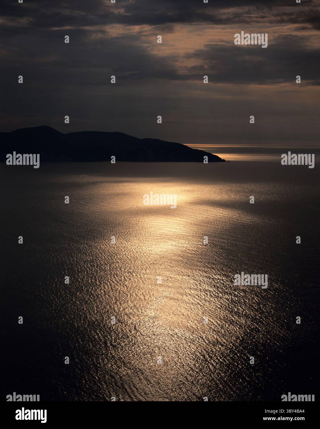 The sun sets behind clouds over Myrtou bay on the west coast of Kefalonia Stock Photo - Alamy