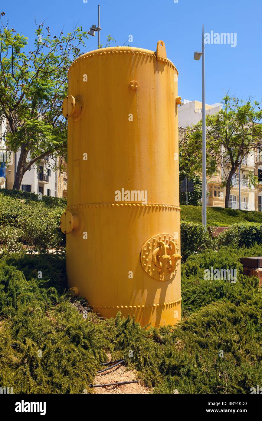 Yellow vertical industrial tank monument in a green park under clear ...