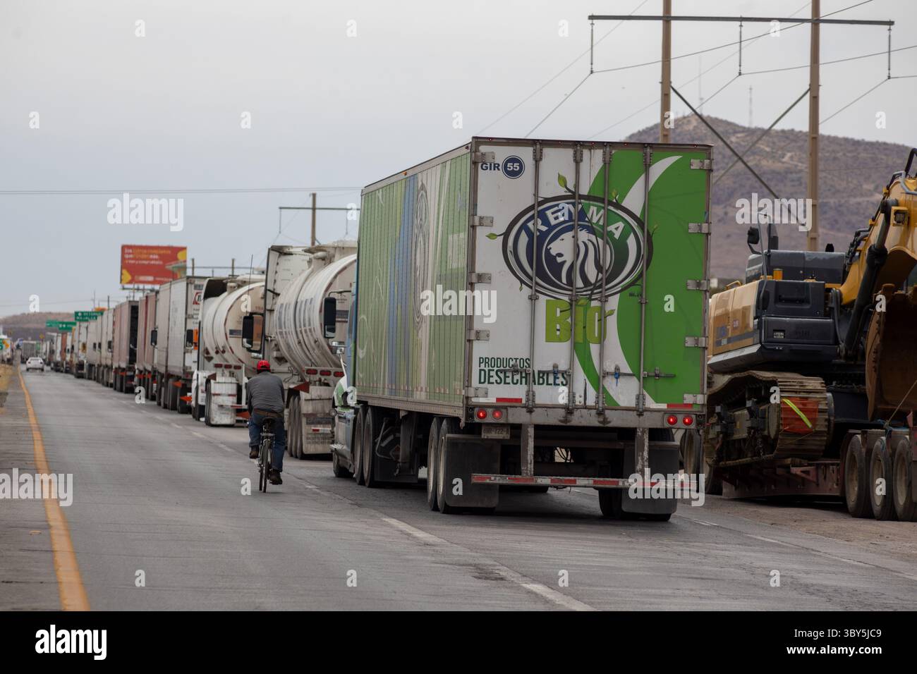 Trucks line up near Ciudad Juarez, a cyclist navigates alongside ...