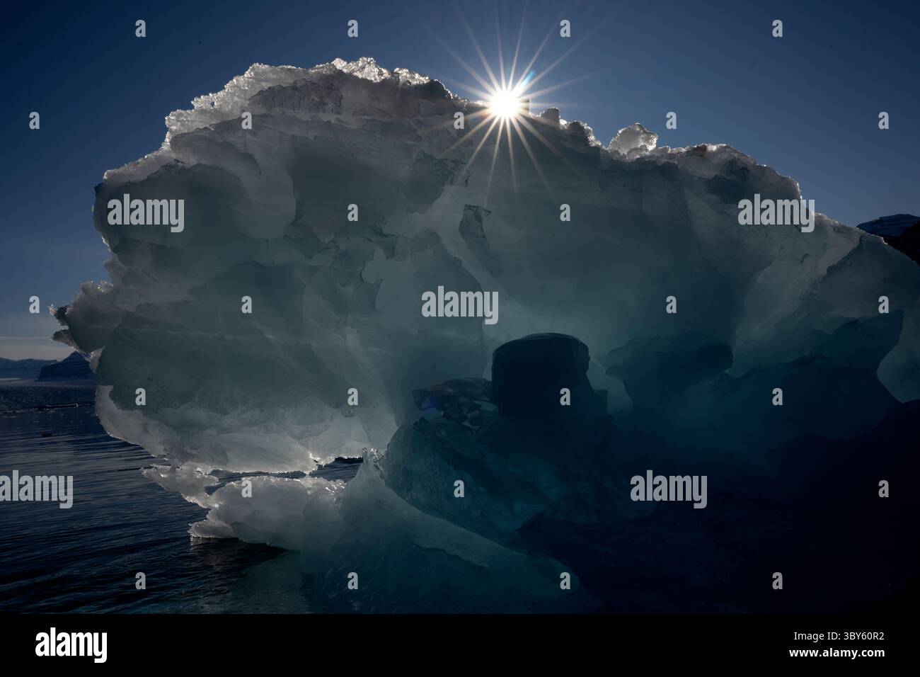 Backlit view of a semi-transparent iceberg with star effect sun, near ...