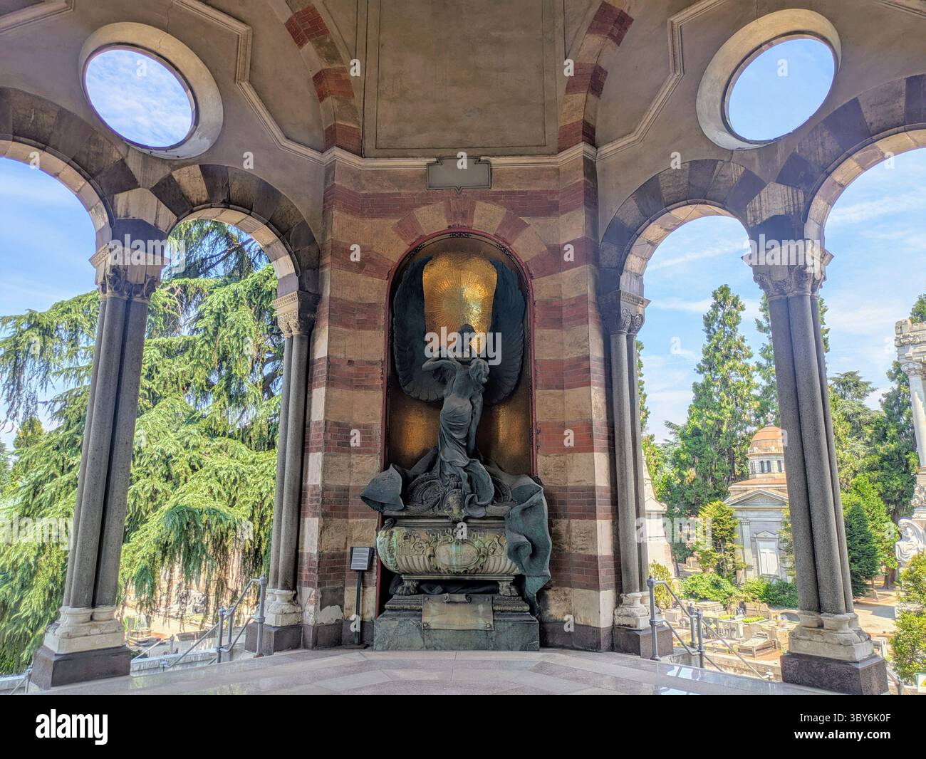 statue of angel under archway with view of trees outside through arches ...