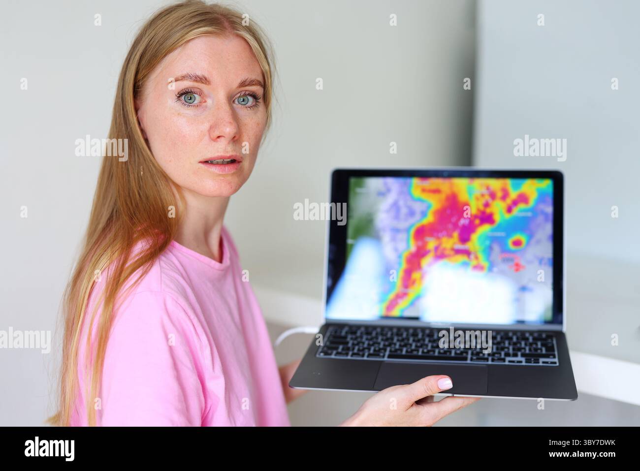 Woman holding laptop with storm radar, severe weather alert, emergency ...