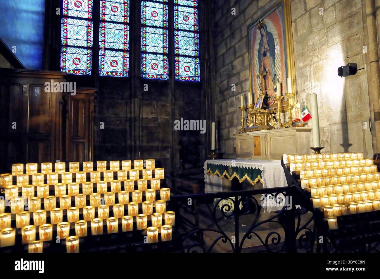 A church interior with candles, an altar and colourful stained glass ...