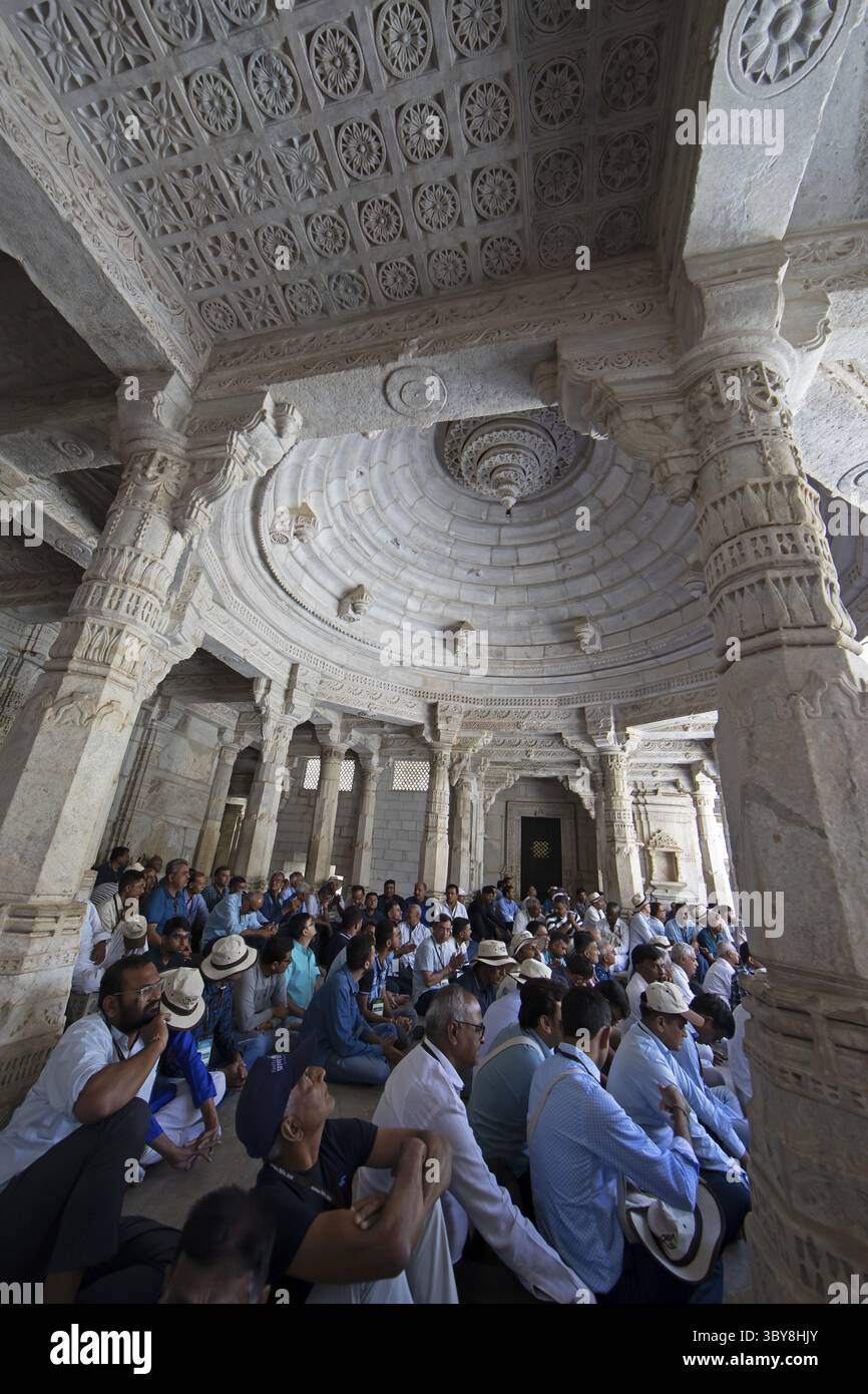 Indian men praying between the white marble pillars in the Adinath ...