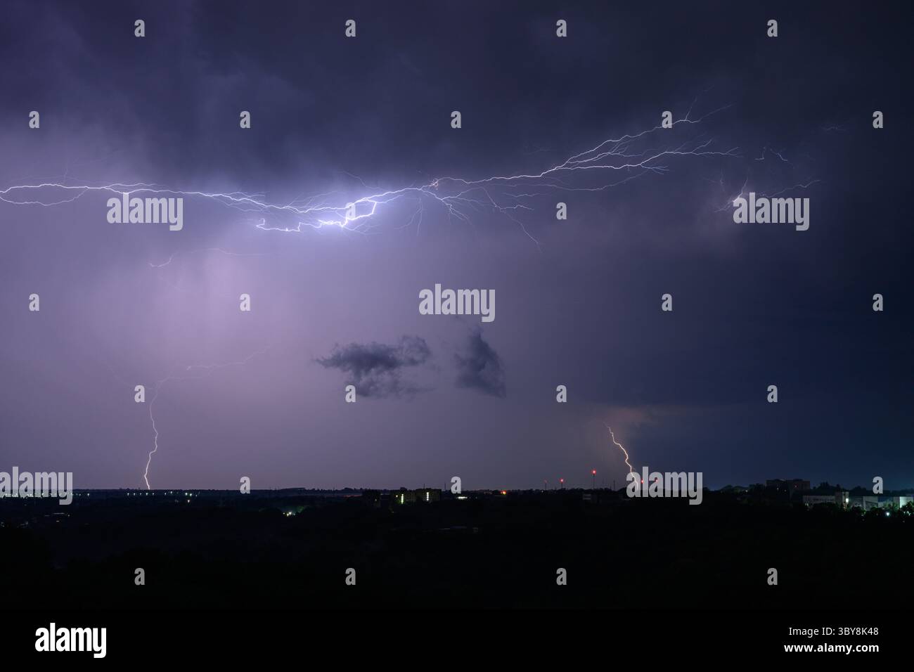 Horizontal lightning flashes across a purple night sky above a ...
