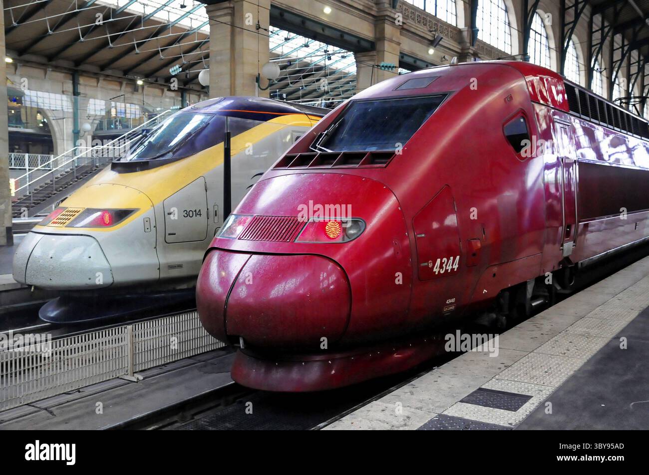 Two colourful TGV trains side by side on the platform of a railway ...