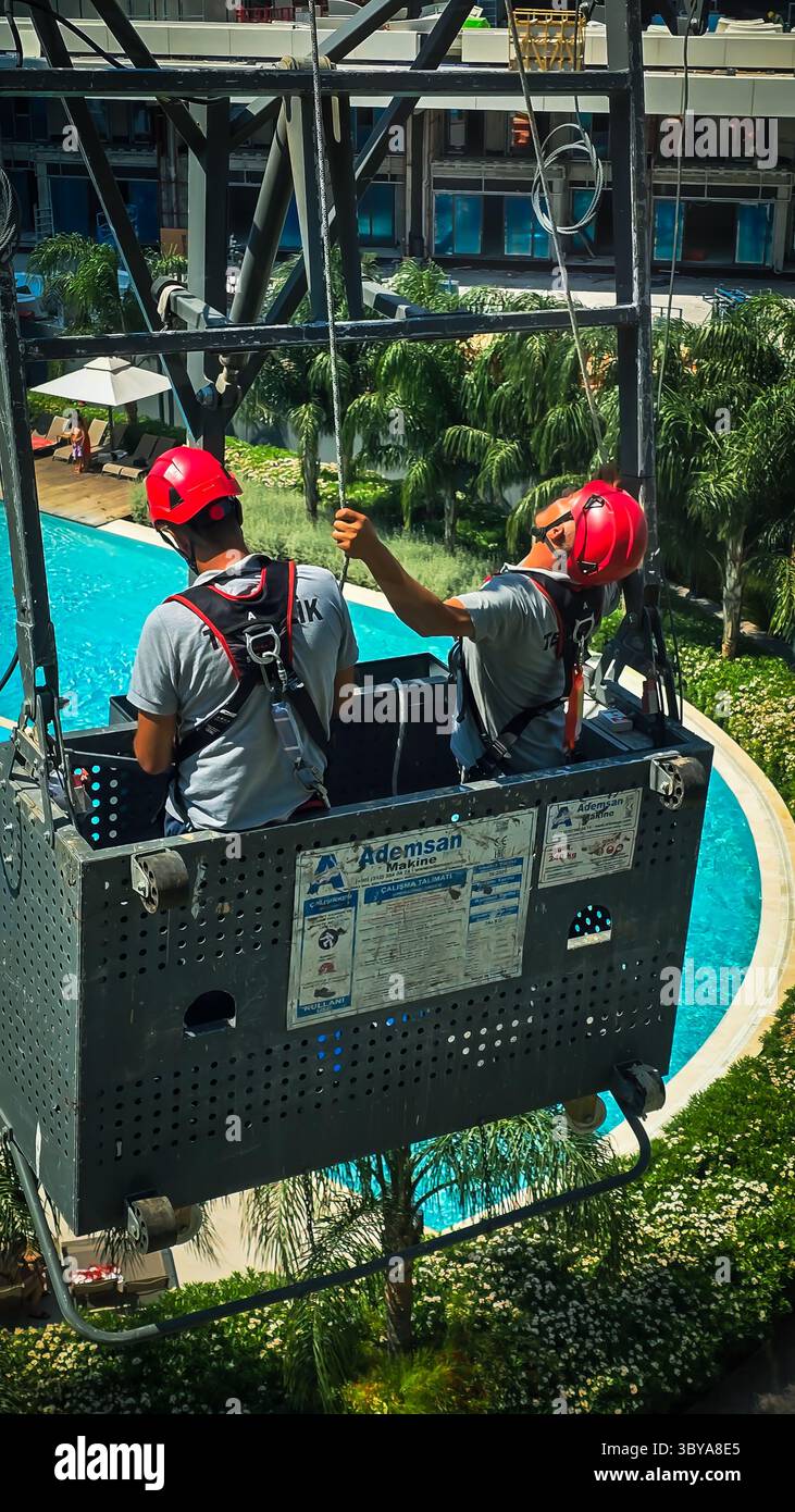 Two construction workers wearing helmets and safety harnesses stand on ...