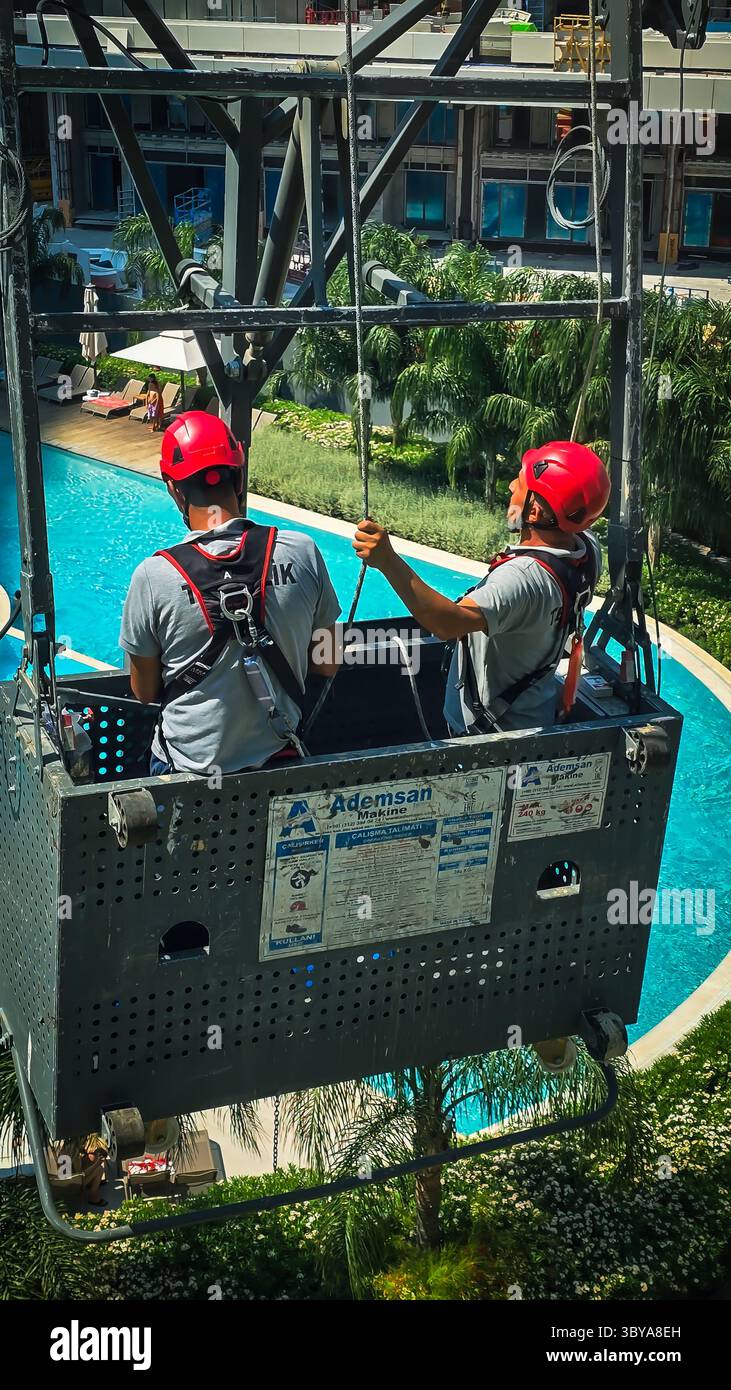 Two construction workers wearing helmets and safety harnesses stand on ...