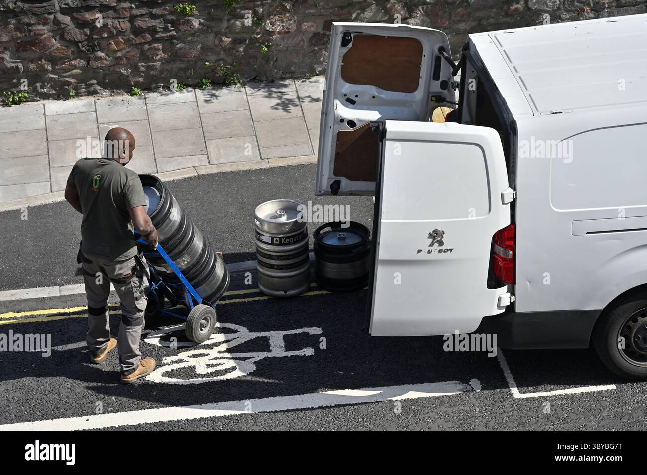 White van with man unloading heavy beer kegs from the rear while parked ...