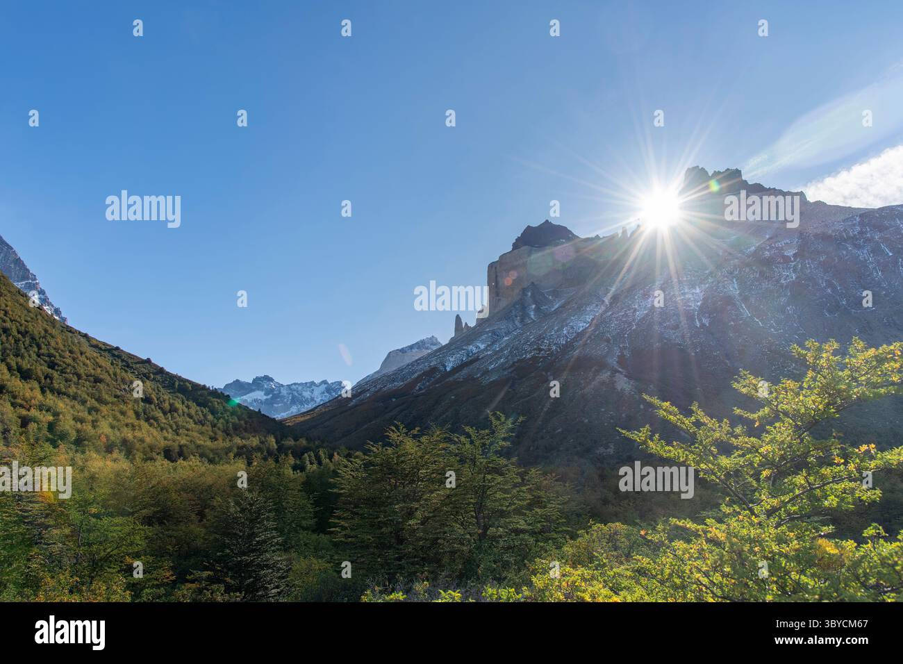 Bright sun rising just above the snowy Horns of the Paine formation in ...