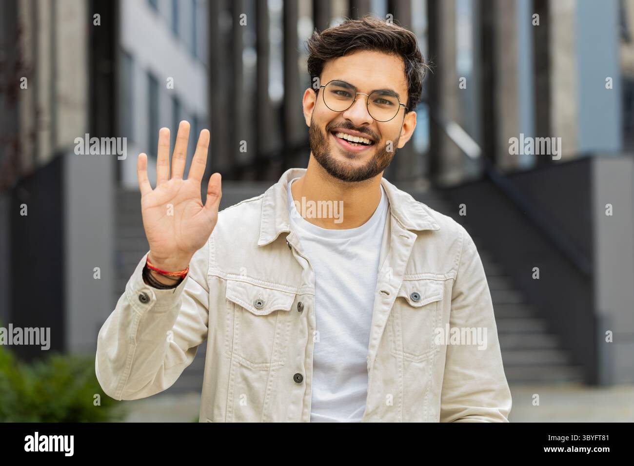Hello. Indian man smiling friendly at camera, waving hands gesturing hi ...